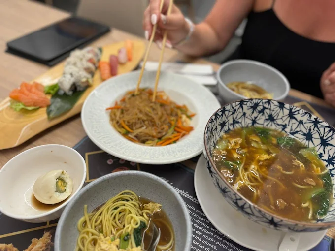 Tavolata con sashimi, spaghetti saltati, zuppa e bao